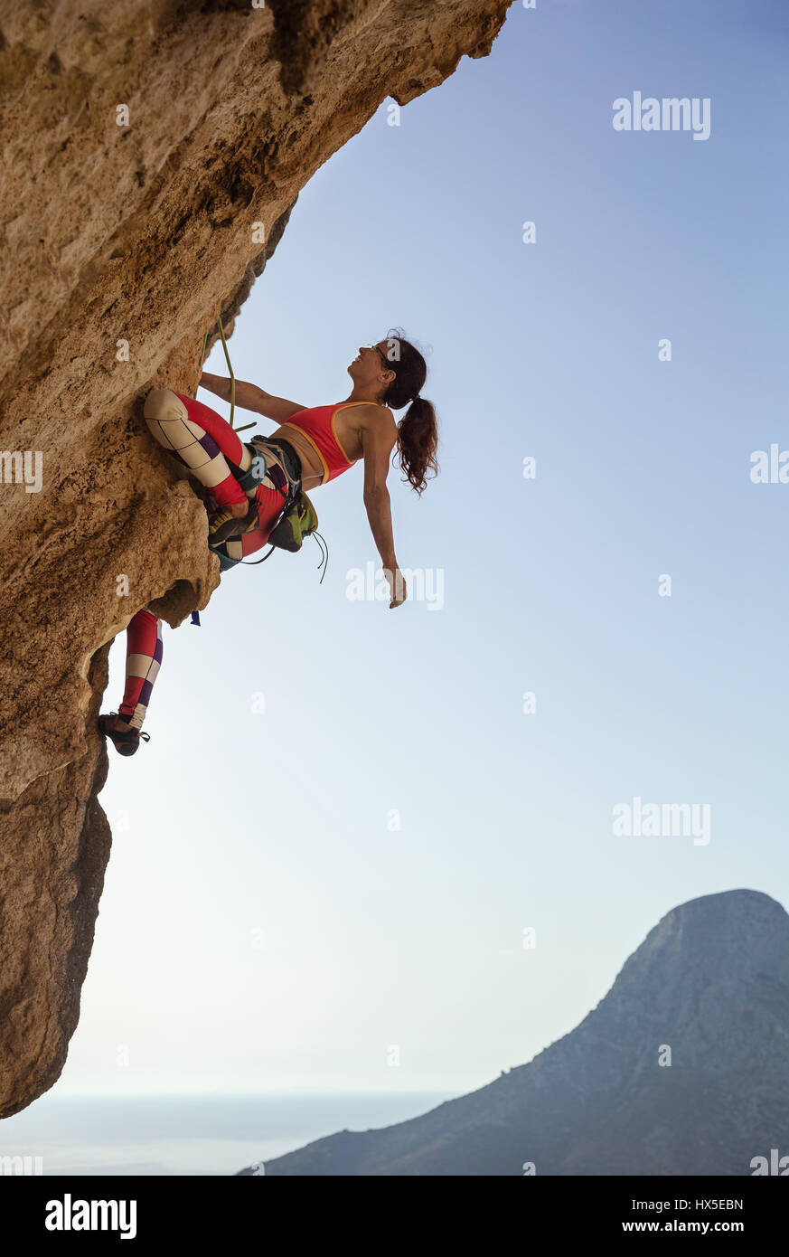 Female rock climber looking up at challenging route on cliff and ...