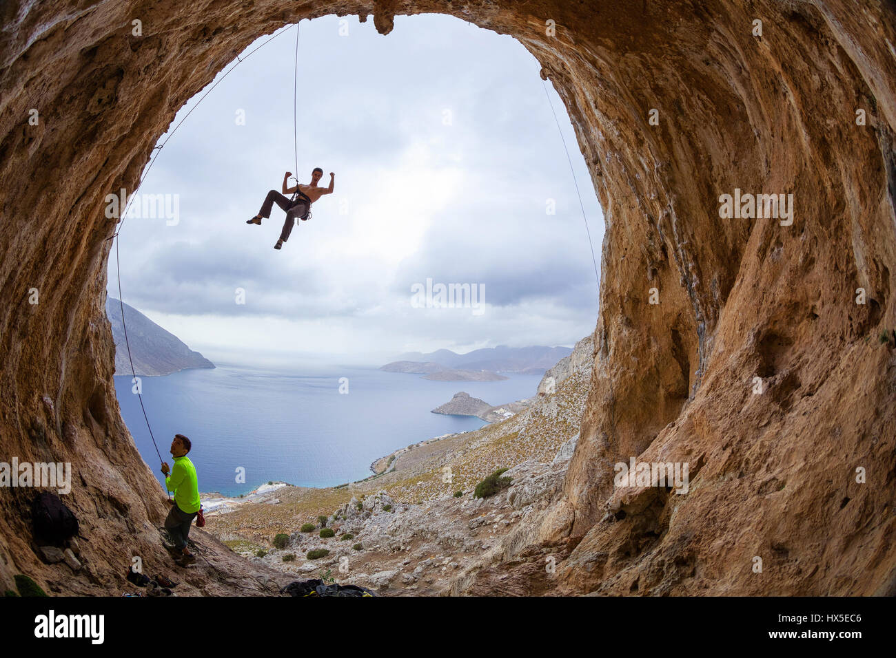 Rock climbers in cave: leading climber flexing muscles jokingly, his ...