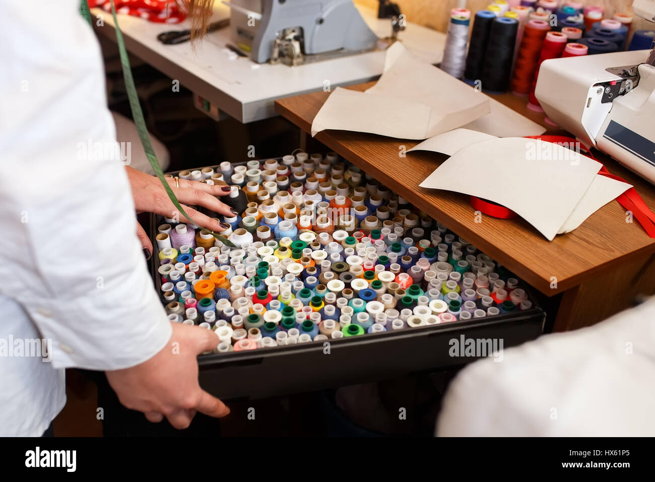 young woman seamstress chooses the tailor thread in box. Tailor ...