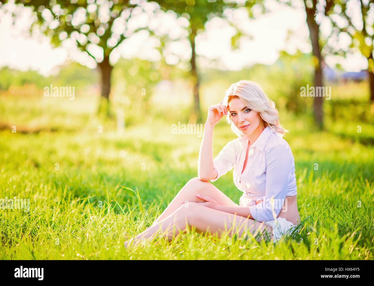 Smiling beautiful young girl sitting on grass in the garden Stock Photo ...