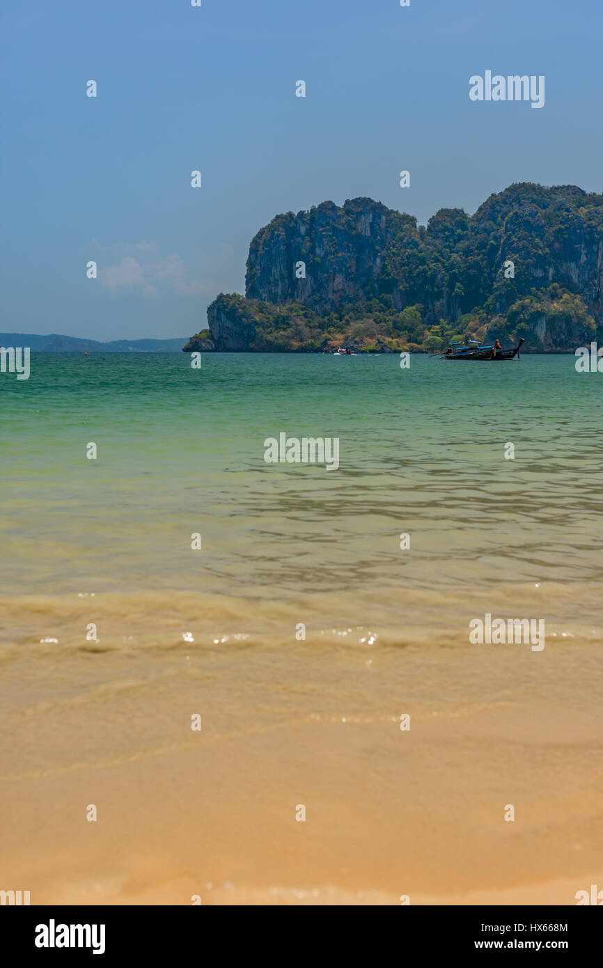 Light waves run up a sandy Thai beach with rocky island back drop Stock ...