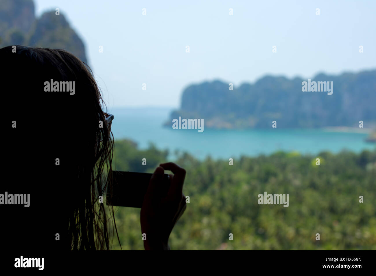 A Young woman taking a photo from a high viewpoint over looking Railay ...