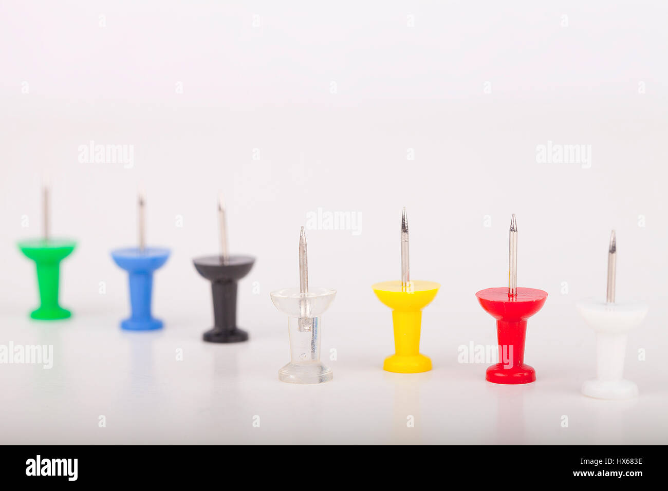 Row of colorful pushpins on a white surface. Push pins isolated on ...