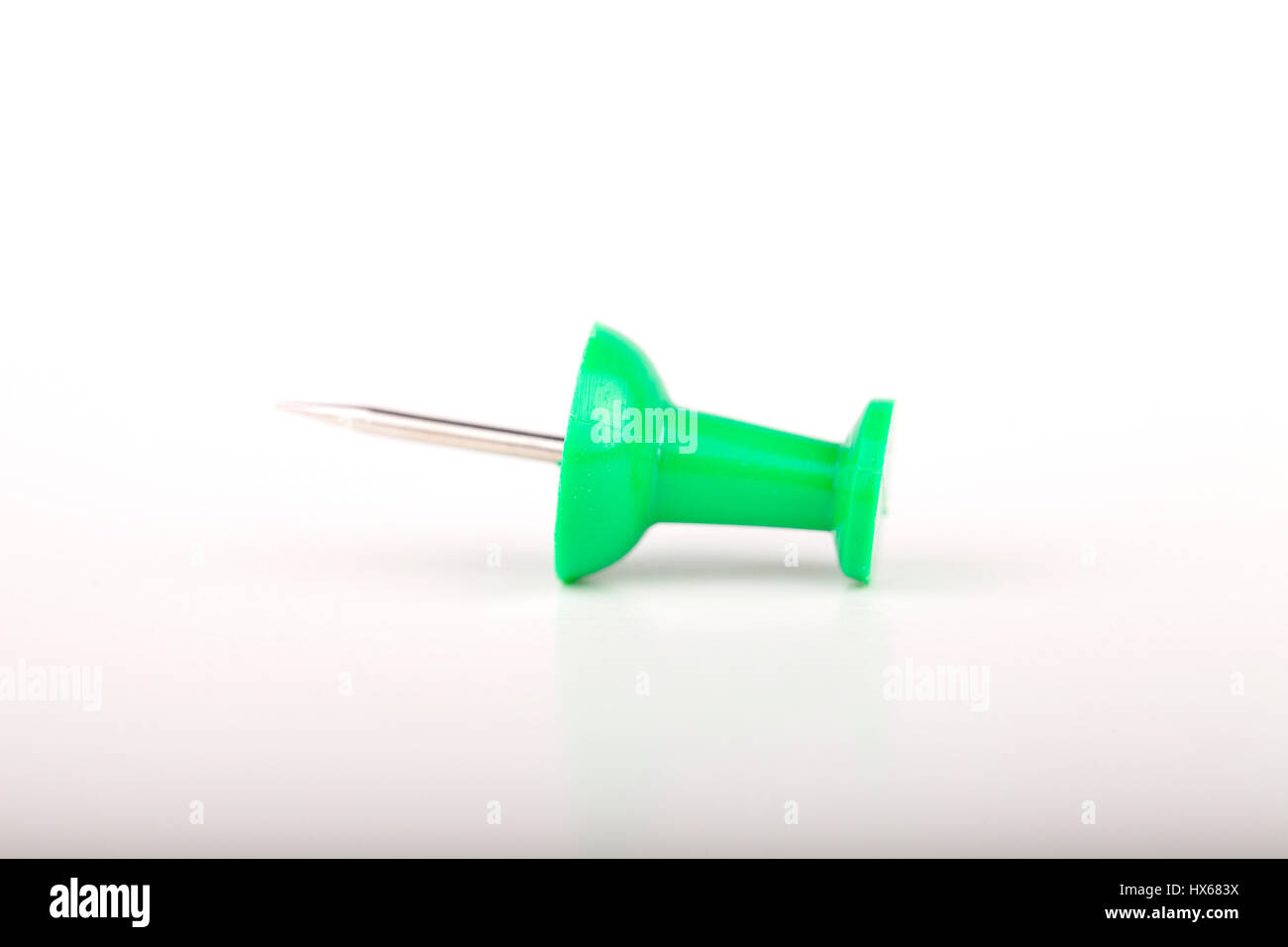 Green pushpin on a white surface. Push pin isolated on white background ...