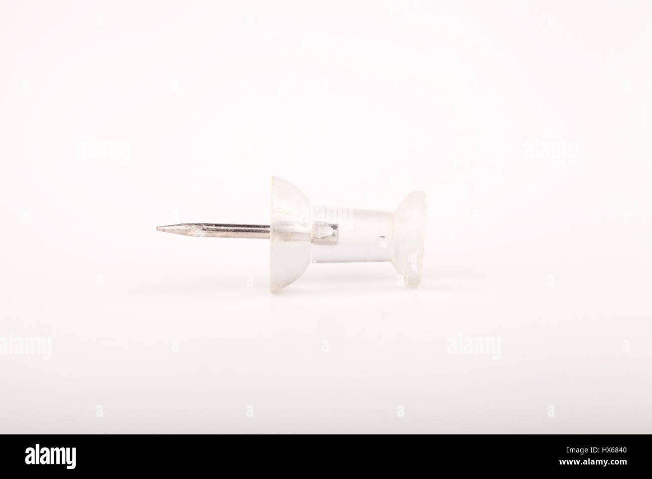 Transparent pushpin on a white surface. Clear push pin isolated on ...