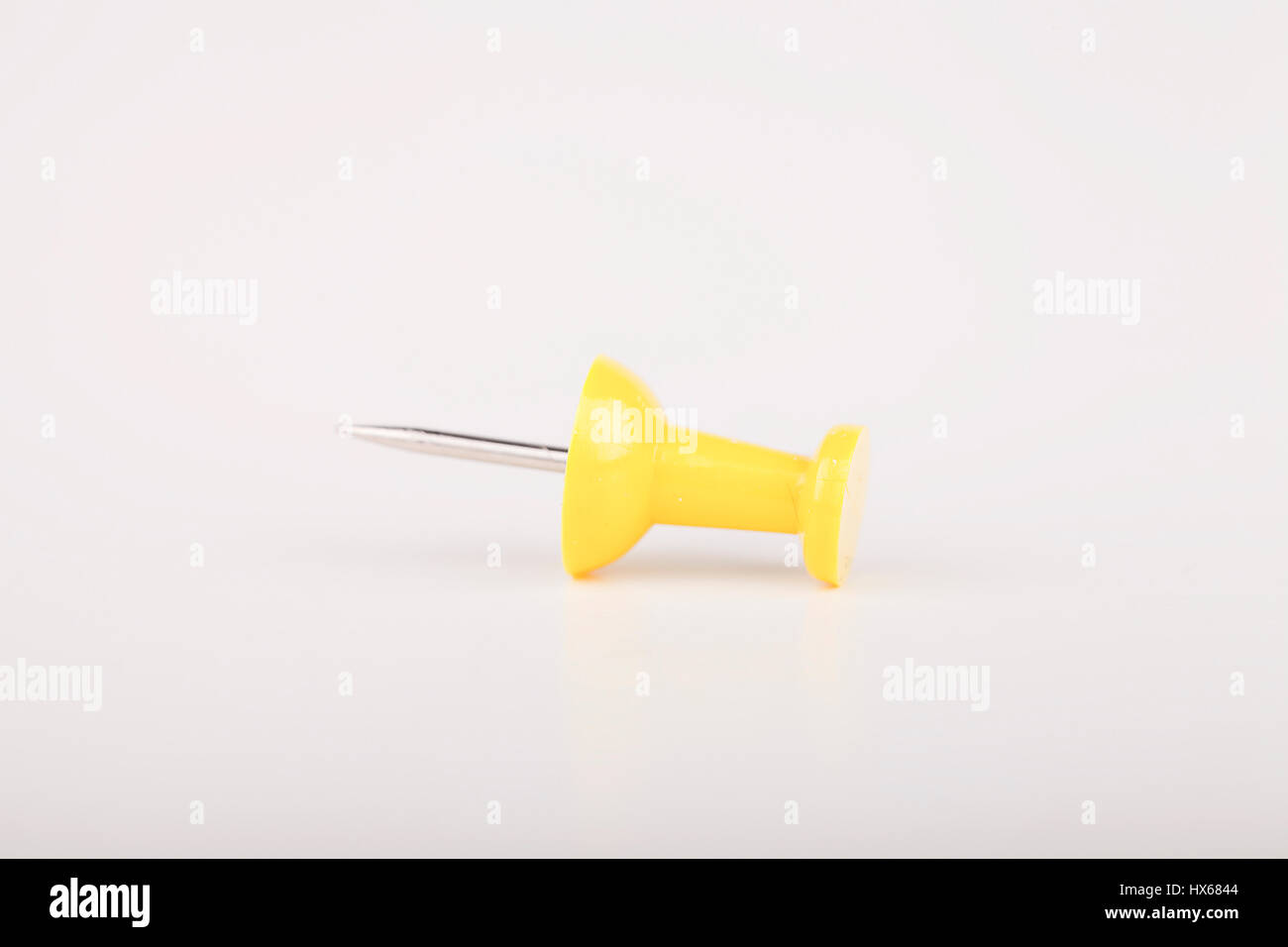 Yellow pushpin on a white surface. Push pin isolated on white ...