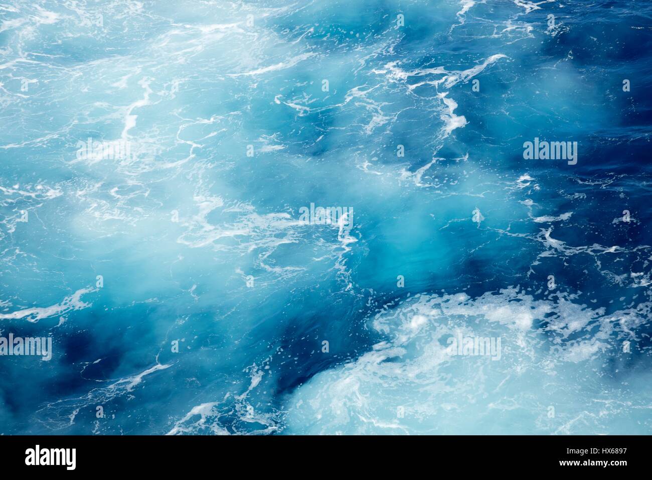 Foaming bubbles from large waves make the azure blue ocean look ...
