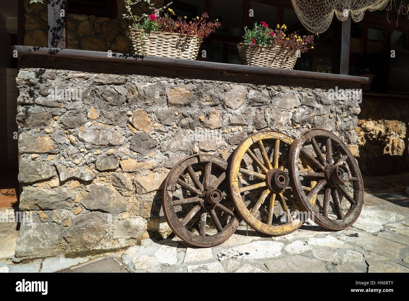 Rustic cart wheels against old stone wall Stock Photo - Alamy