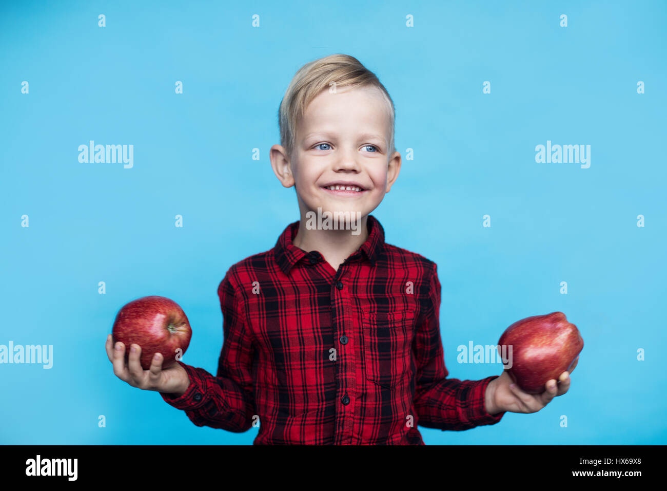 Handsome little kid with fruits. Studio portrait over blue background ...