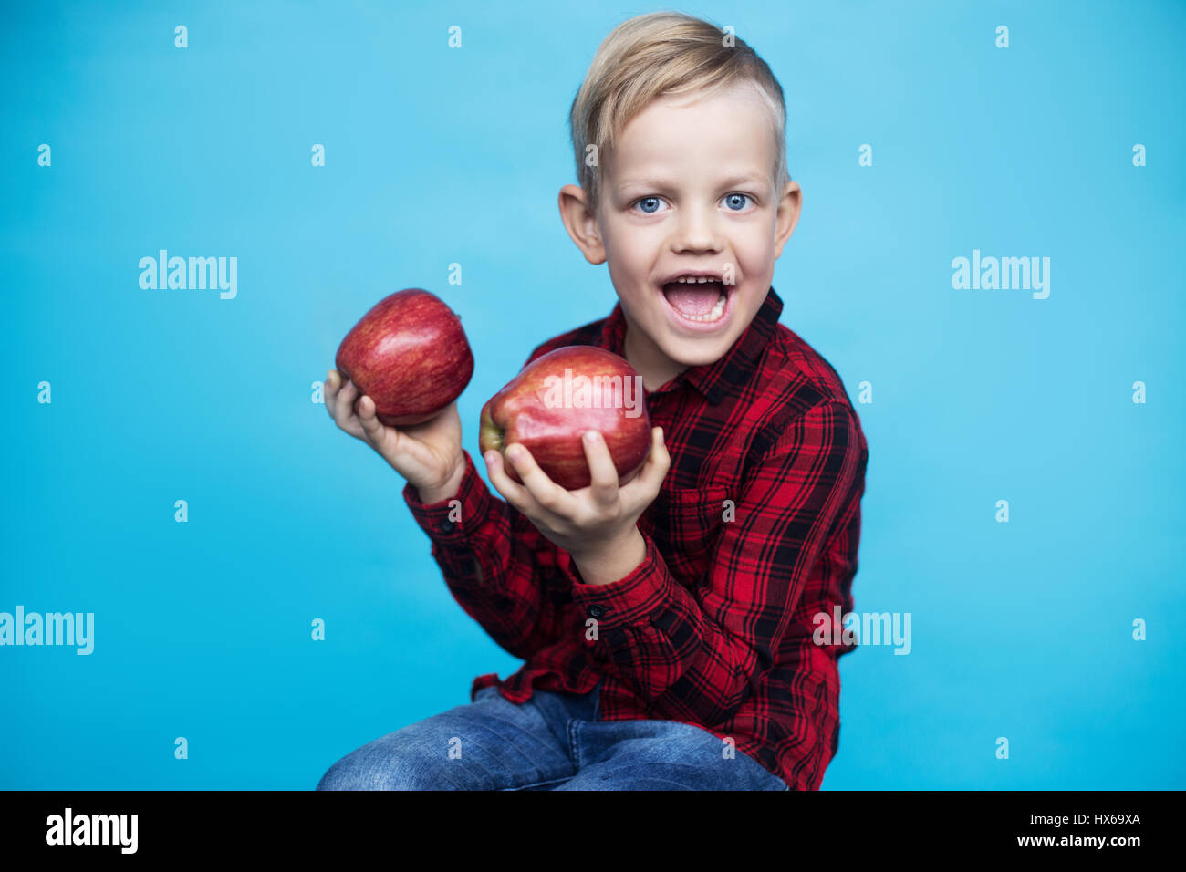 Handsome little kid with fruits. Studio portrait over blue background ...