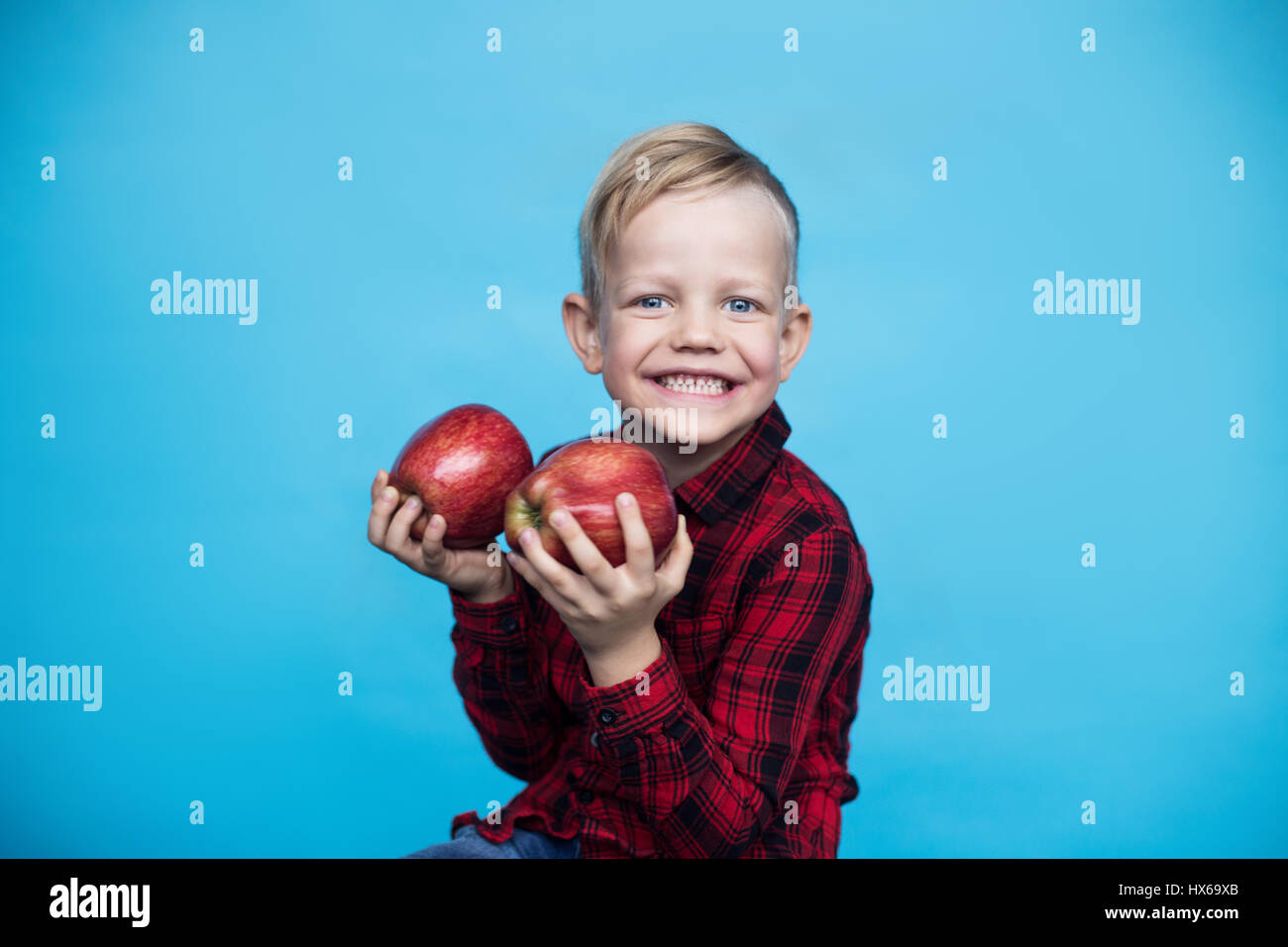 Handsome little kid with fruits. Studio portrait over blue background ...