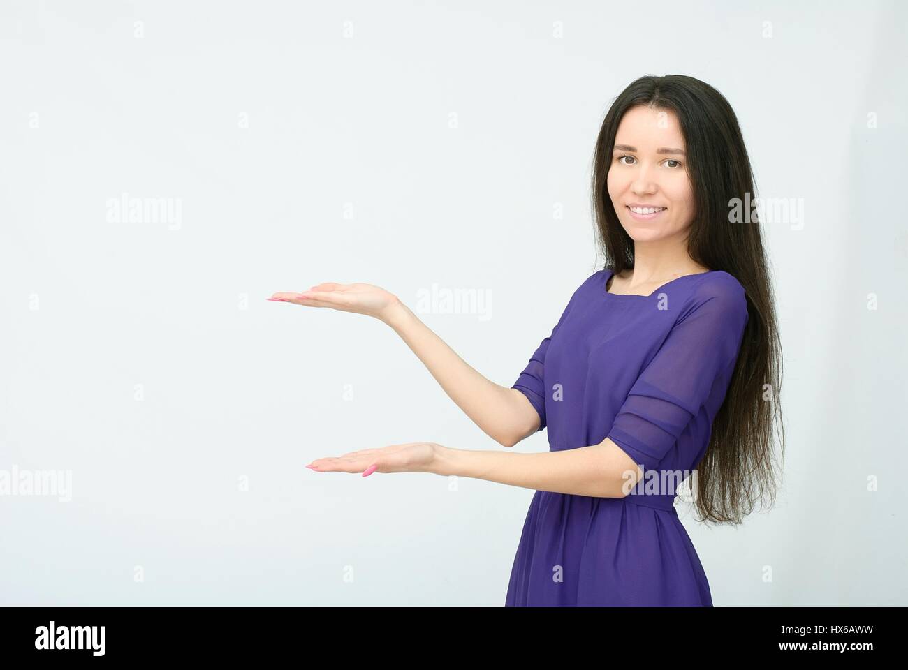 beautiful young woman standing with her hand up against white ...