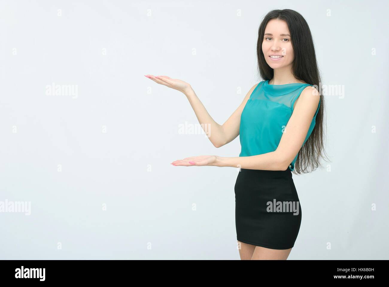 beautiful young woman standing with her hand up against white ...
