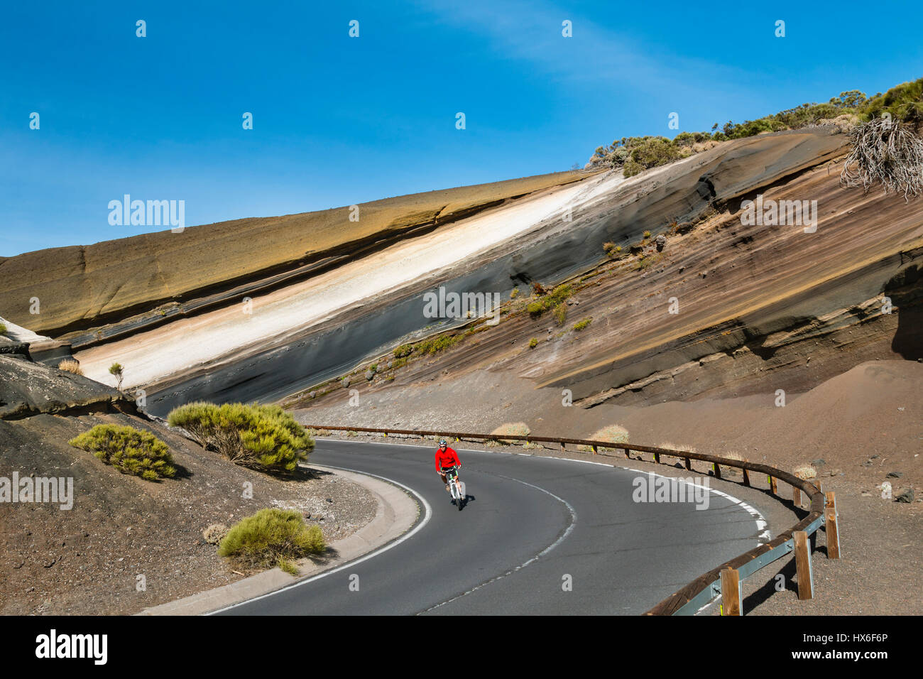 TENERIFE - OCTOBER 14: A mountain biker cycling between colorful volcanic rock layers in a bend ...