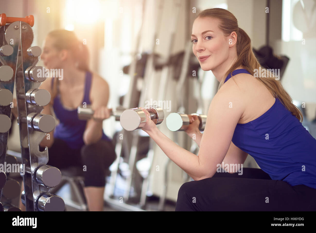 Fit healthy woman working out with weights in front of a large wall ...