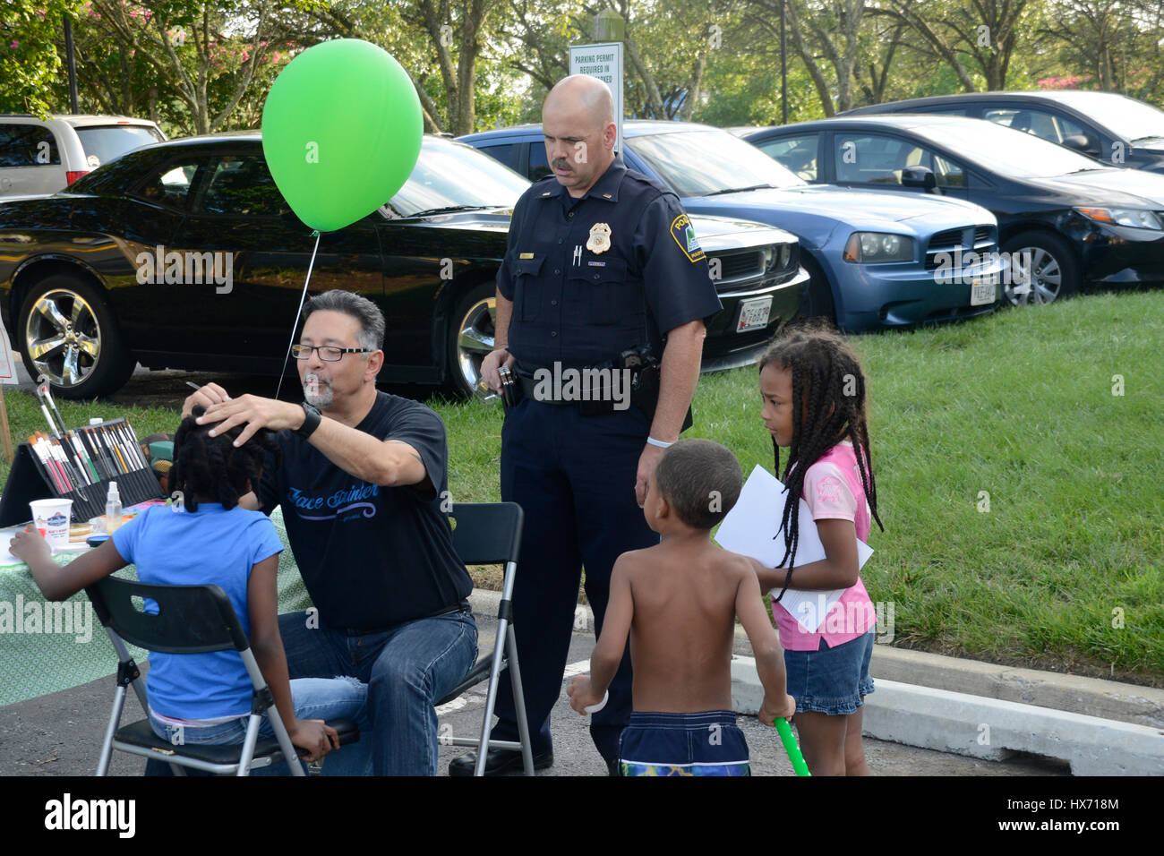 Police officer watches a man doing face painting at a city festival in ...