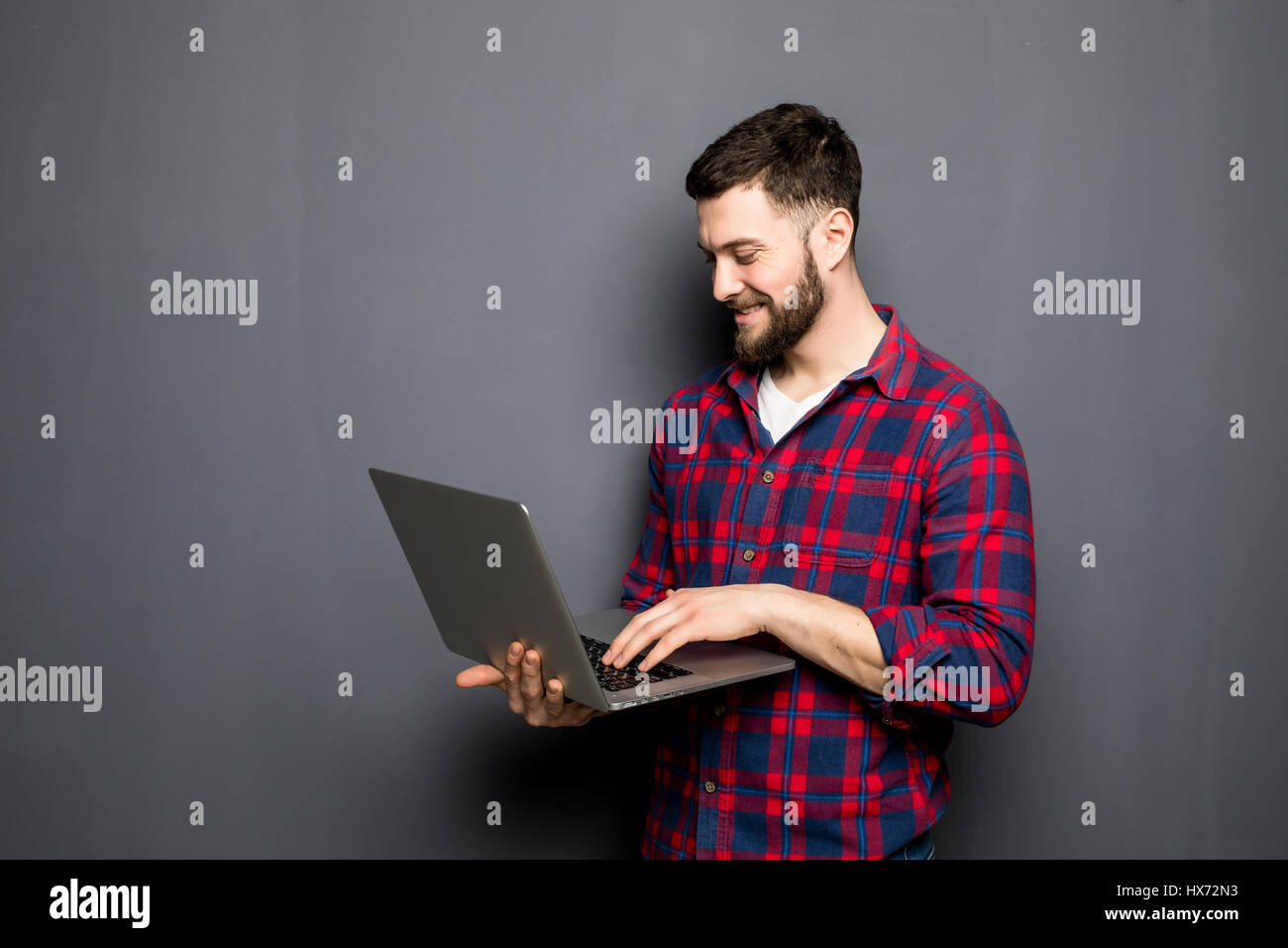 Handsome casual man showing blank laptop screen over gray background ...