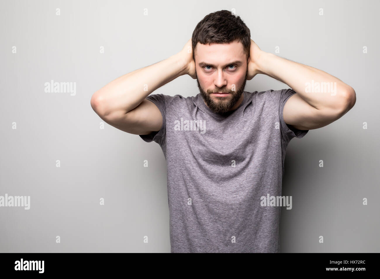 Shocked dazed young man in plaid shirt holding head with both hands ...