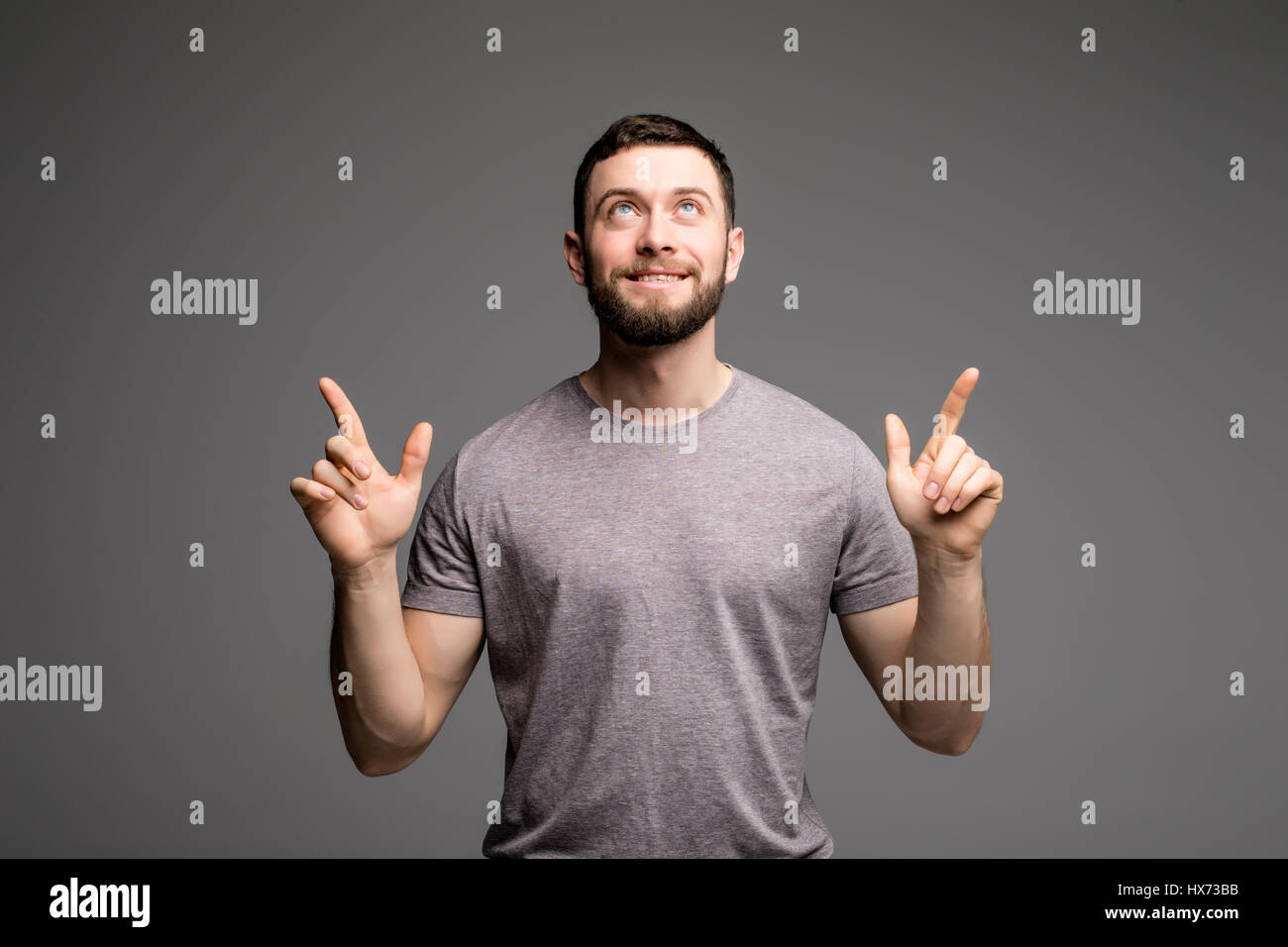 Happy cheerful young guy gesturing up with fingers Stock Photo - Alamy