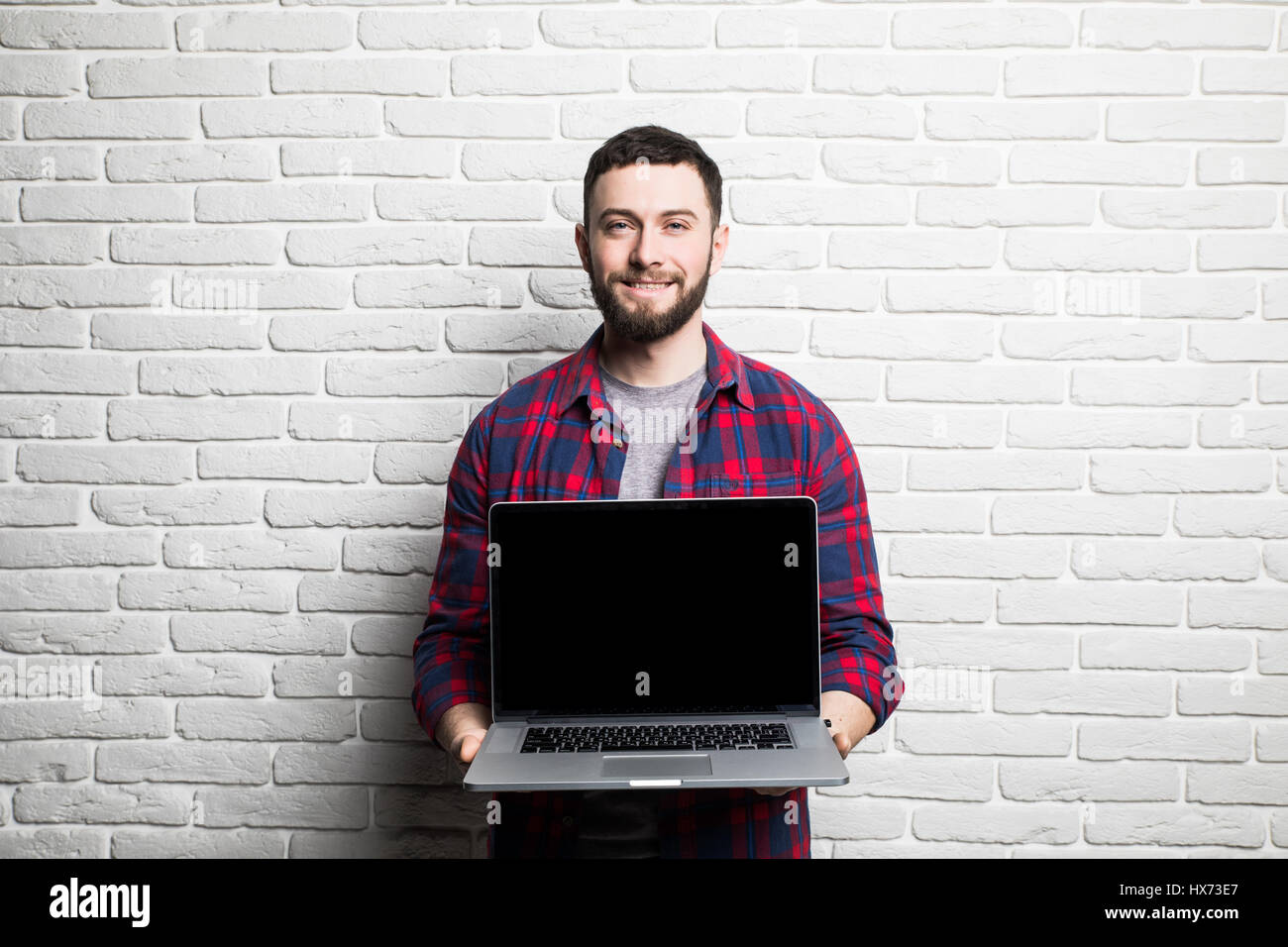 Happy young man show laptop with screen against brick wall Stock Photo ...