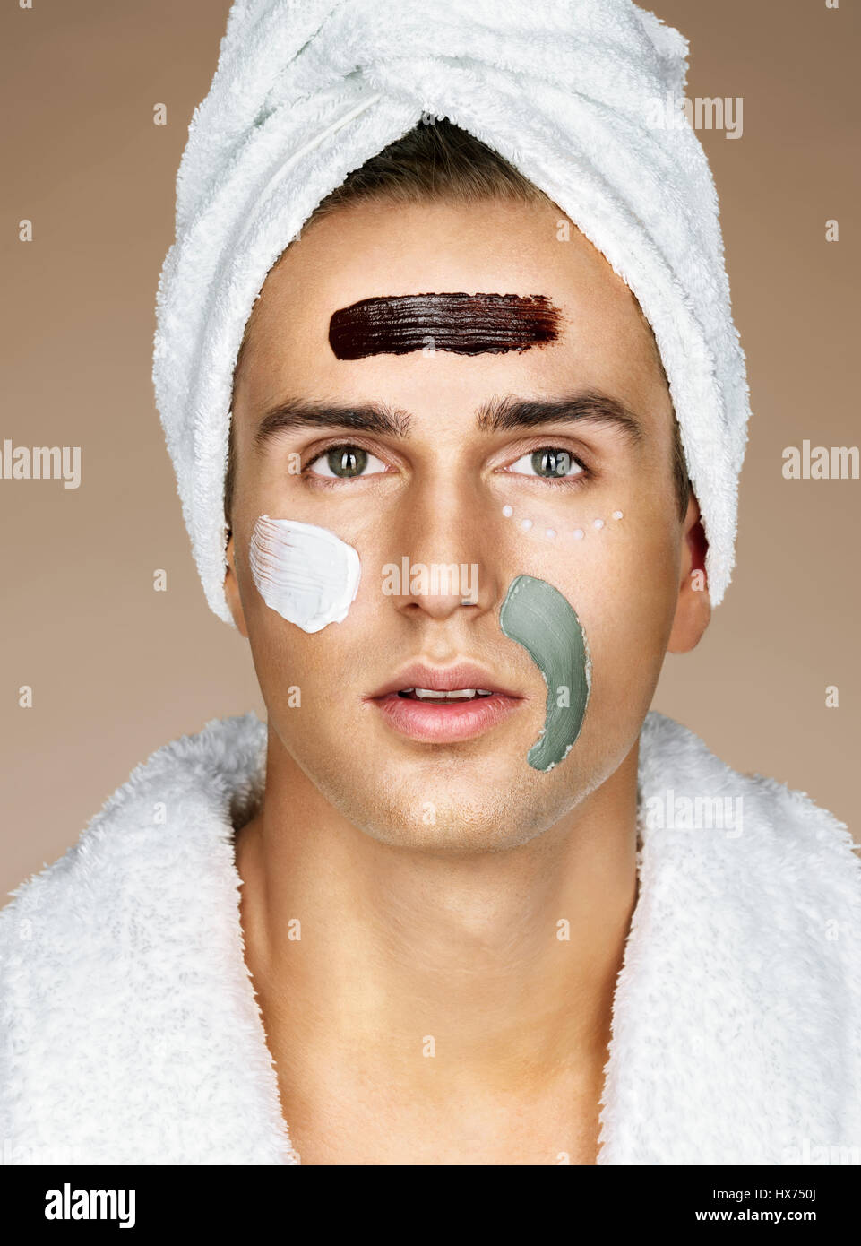 Handsome man with three different face masks (chocolate, cream and clay ...