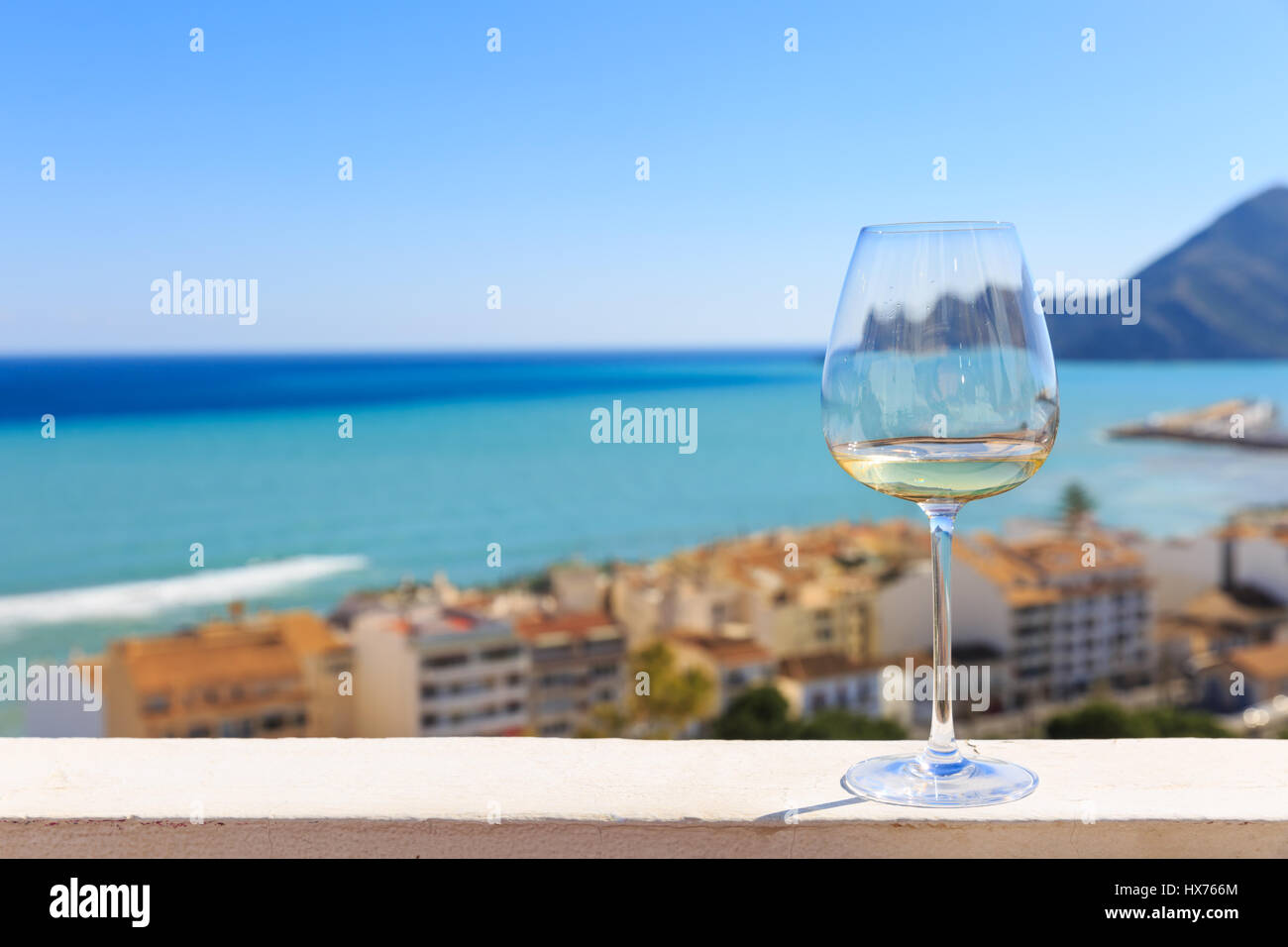 White wine glass against sunny Mediterranean scene with the sea and ...