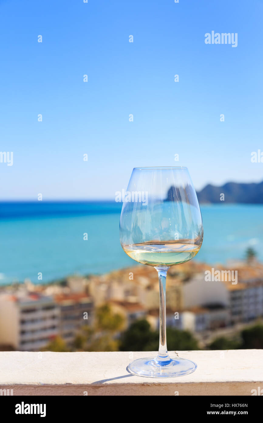 White wine glass against sunny Mediterranean scene with the sea and ...