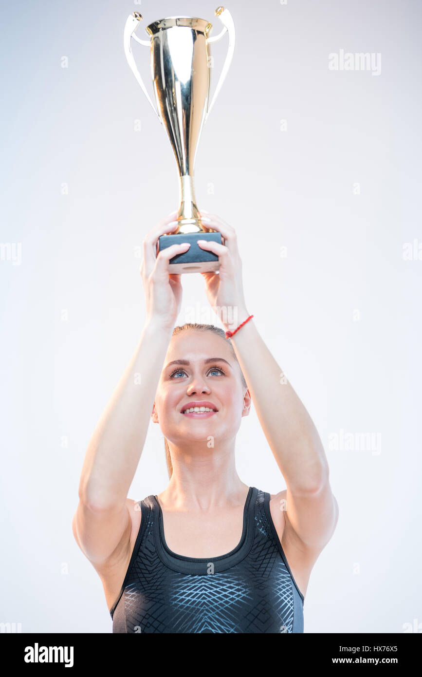 smiling young woman holding trophy in hands above head Stock Photo - Alamy