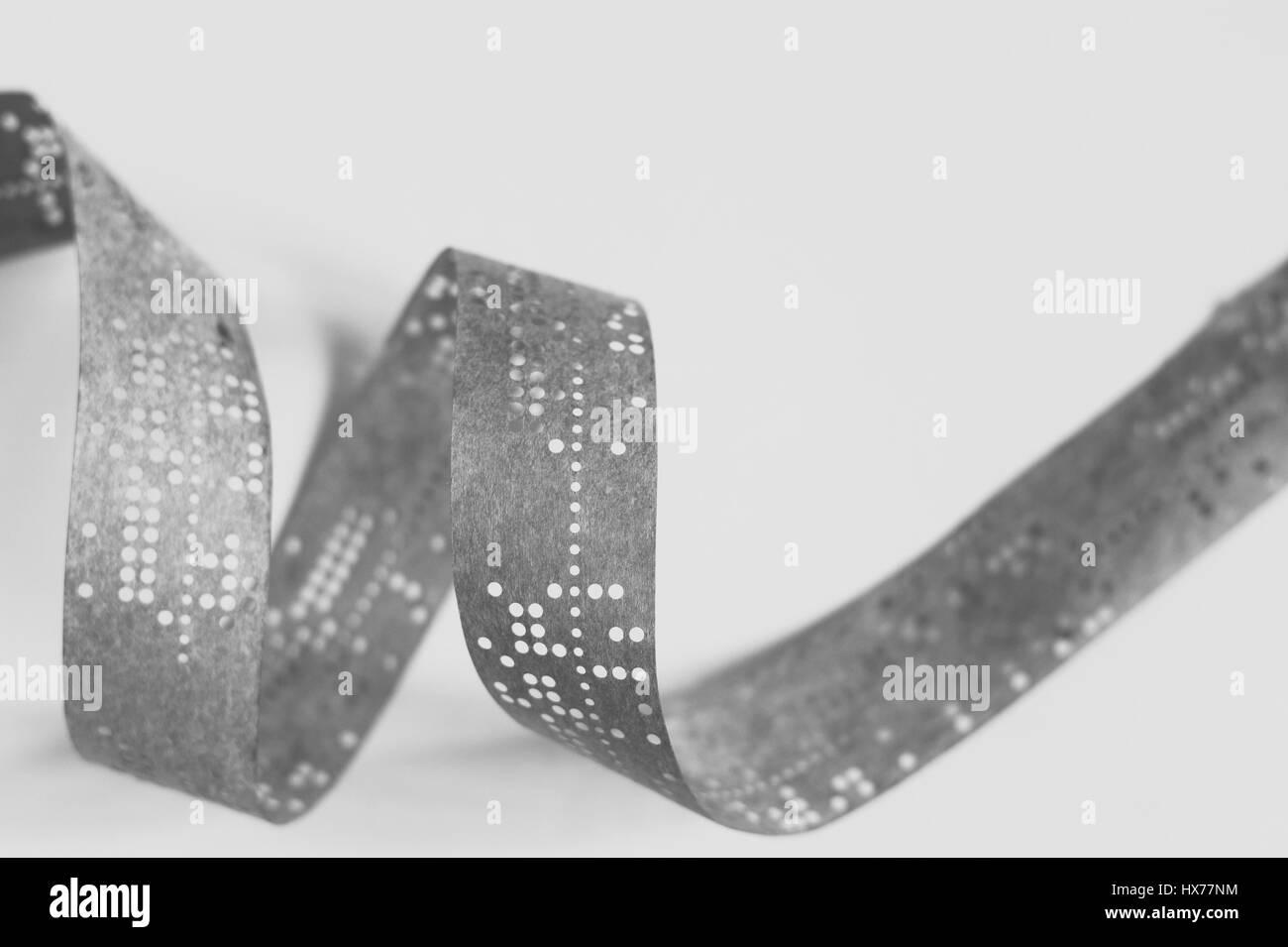 Strips of old punched tape on white surface Stock Photo - Alamy