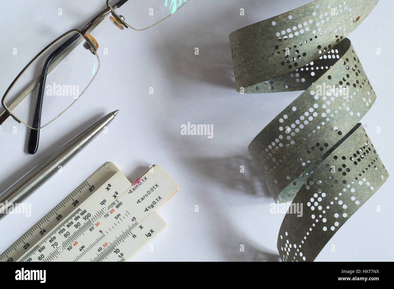 Strips of old punched tape on white surface Stock Photo - Alamy