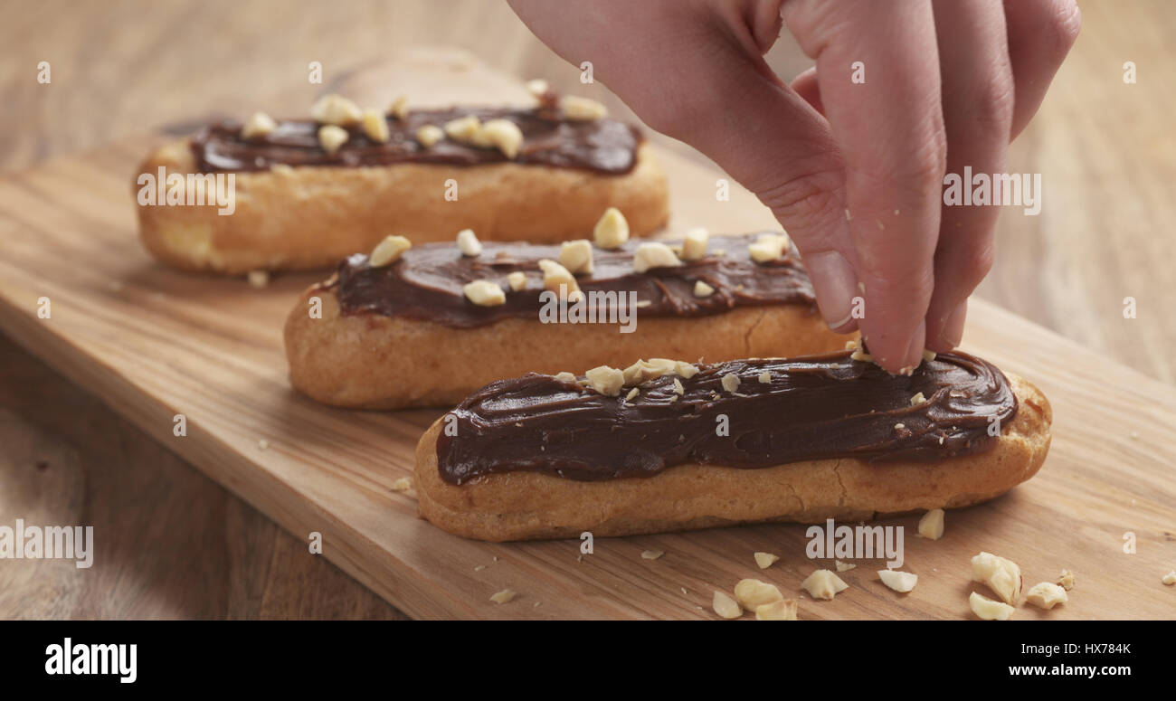 decorating eclairs with hazelnuts on wood board, 4k photo Stock Photo ...
