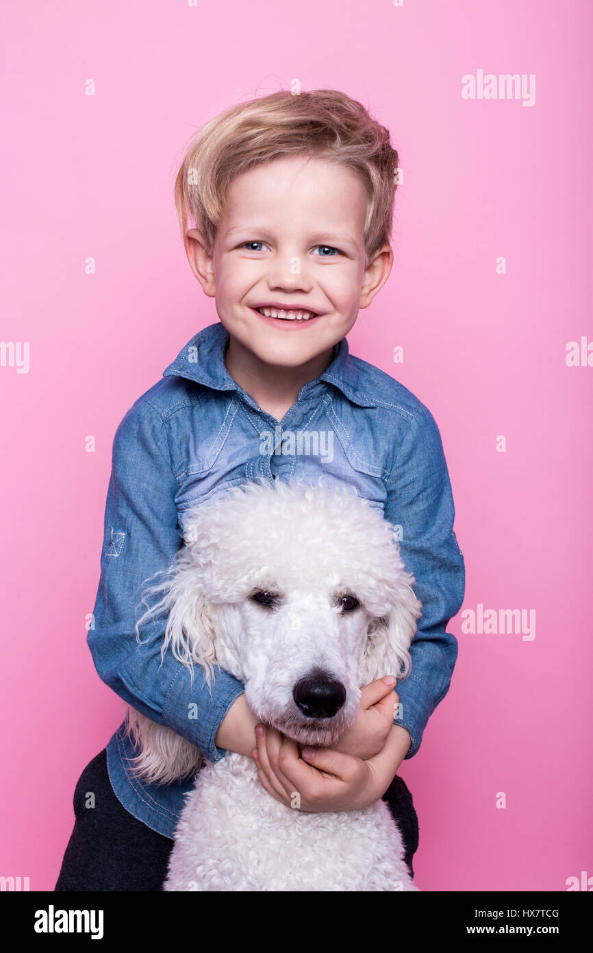 Beautiful boy with Royal Standard Poodle. Studio portrait over pink ...