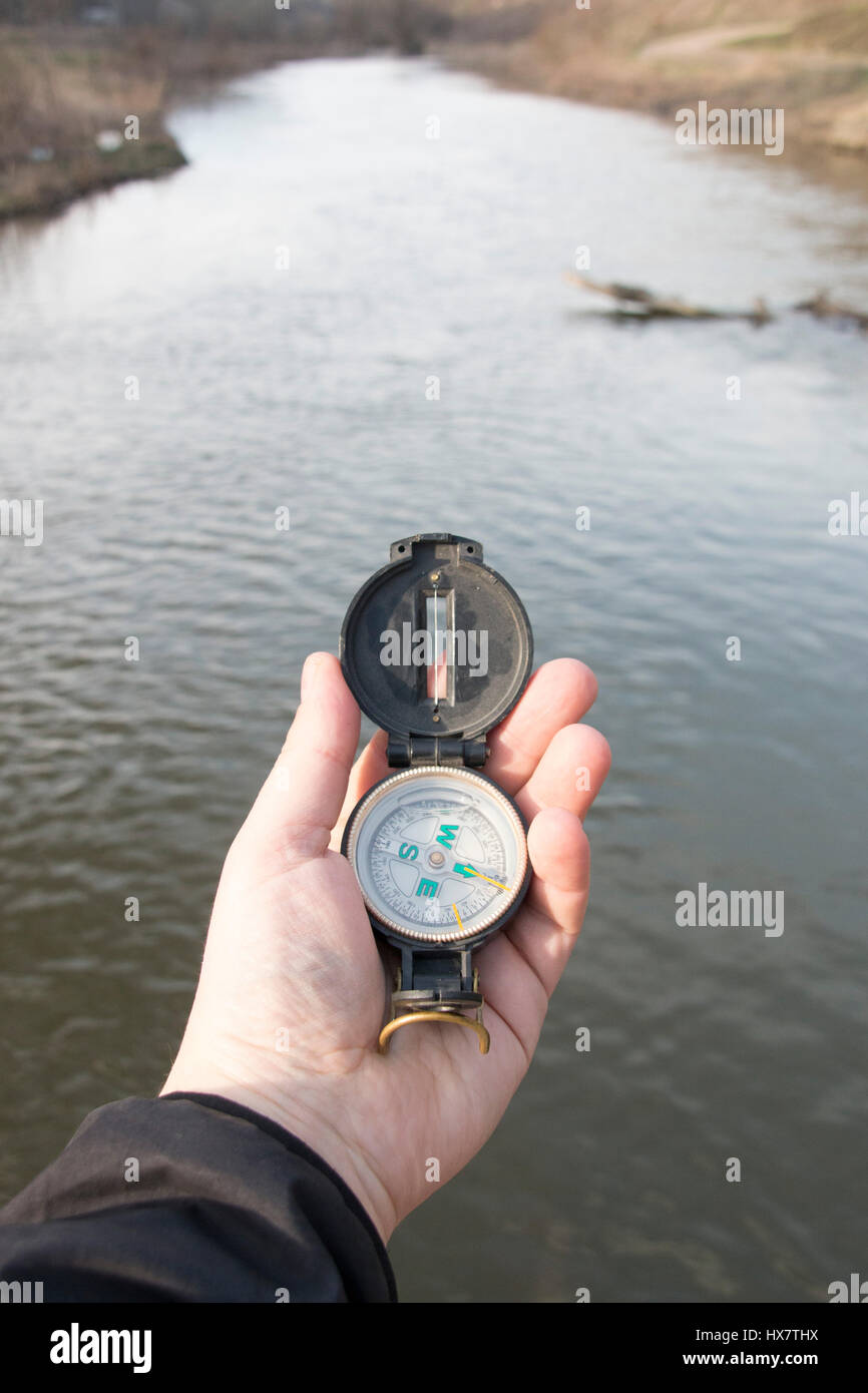 Man traveler holding a compass. On the background - beautiful river ...