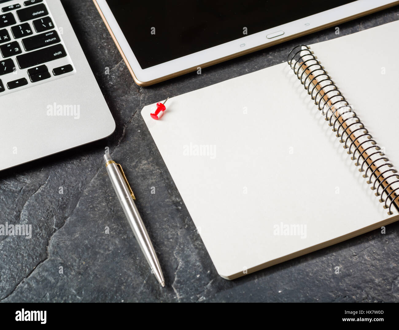 Laptop, pen and notebook with a spring on a black background. Clean ...
