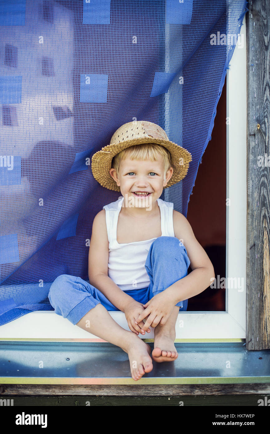 Outdoor portrait: Young boy sit on the window sill, smiling Stock Photo ...