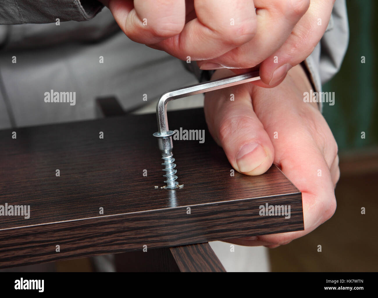 Assembling of furniture, closeup hex wrench in hand, furniture screw ...