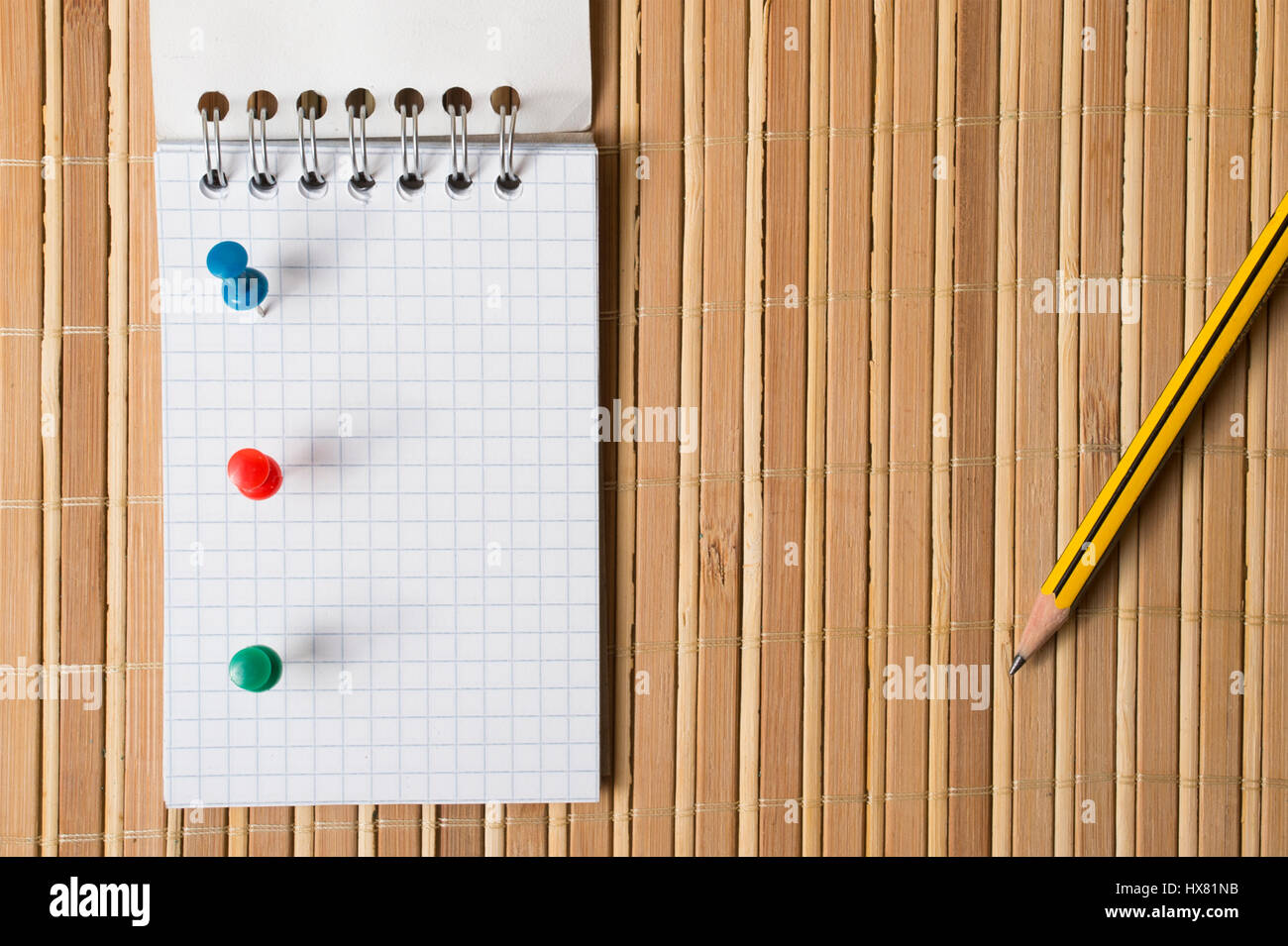 Pins, notepad and pencil on a bamboo table Stock Photo - Alamy
