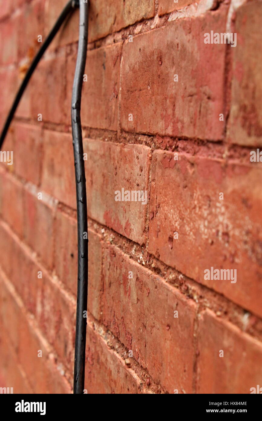 A wire hanging on a red brick wall of an apartment building Stock Photo ...