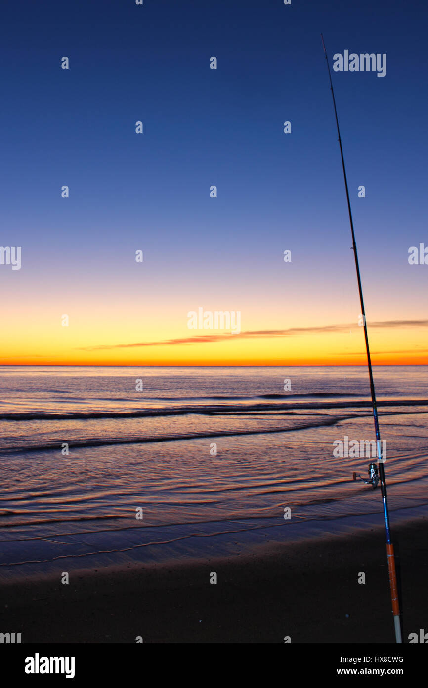 A fishing rod on a beach at the sunset Stock Photo - Alamy