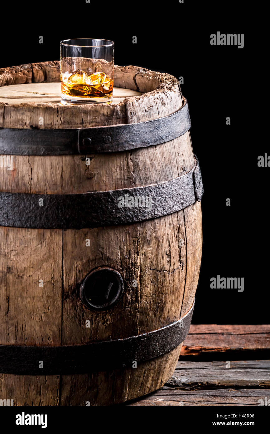 Glass of aged brandy or whiskey on the rocks and old oak barrel Stock ...