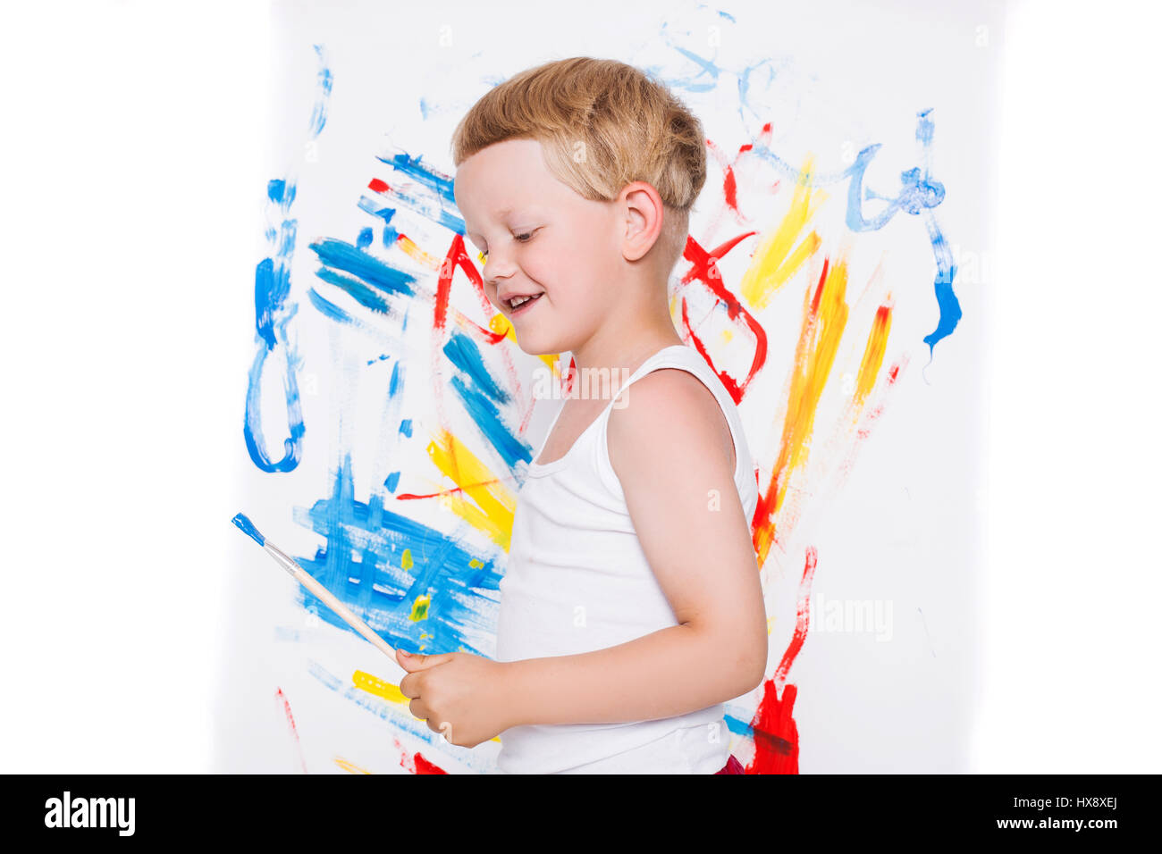 Little messy kid painting with paintbrush picture on easel. Education ...