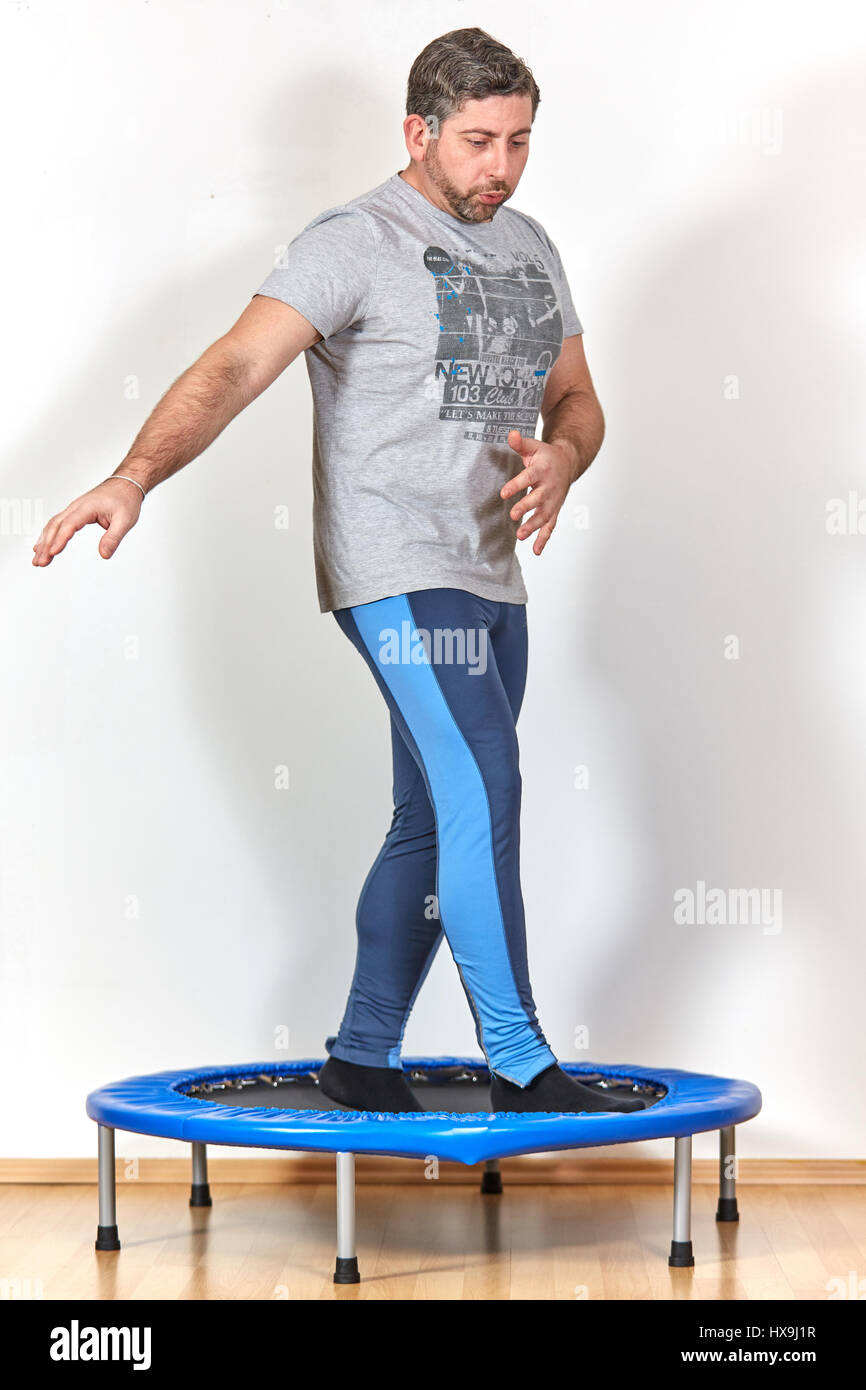 Caucasian man doing fitness exercises at home jumping on trampoline ...