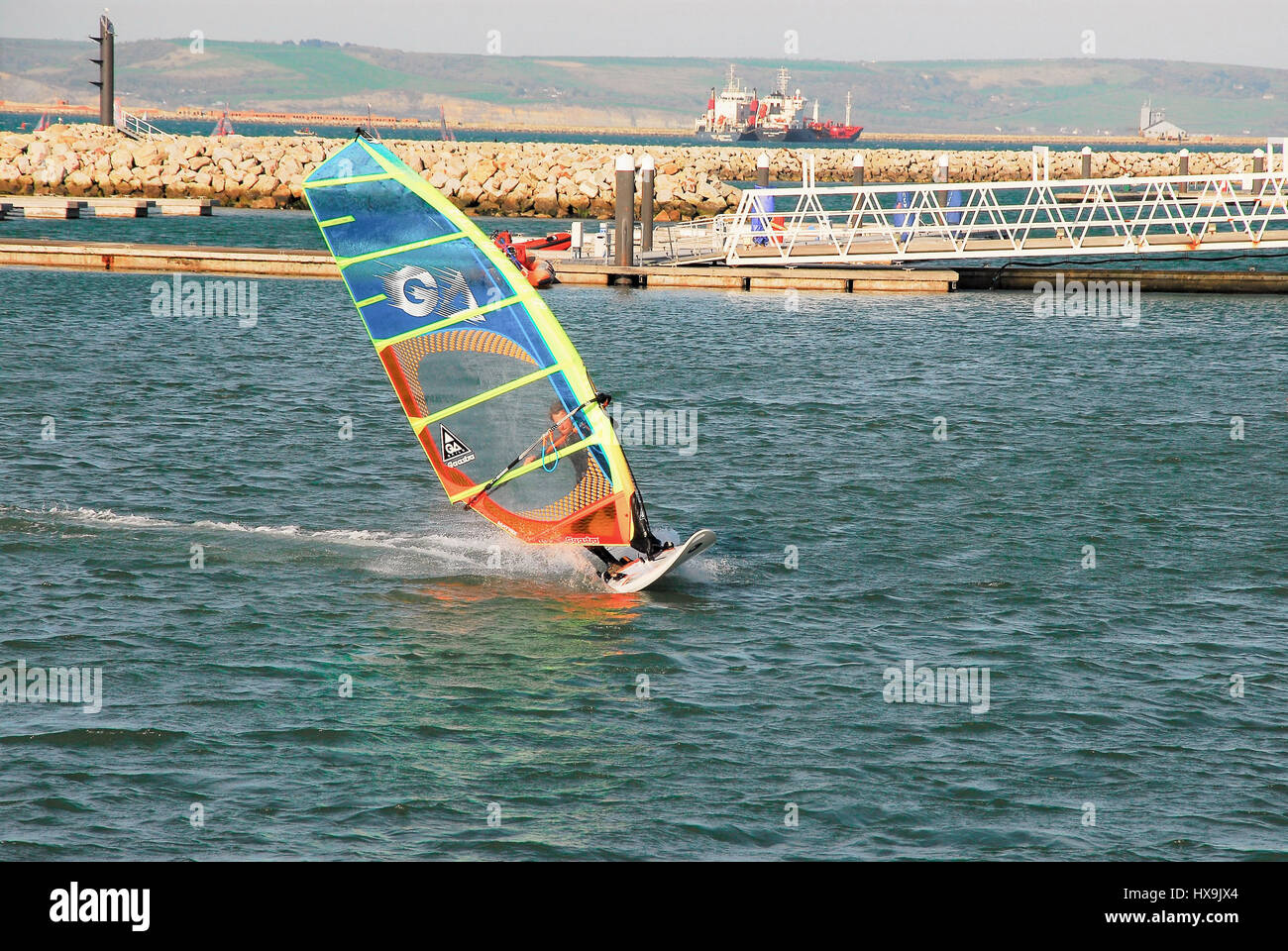 Portland, UK. 25th Mar, 2017. A windsurfer achieves a perfect, high ...