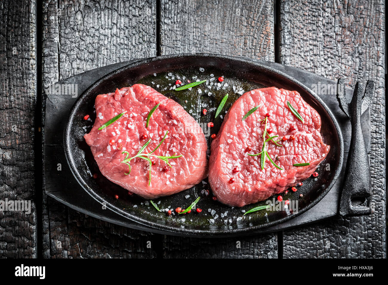 Grilling red meat with herbs on black burning table Stock Photo - Alamy
