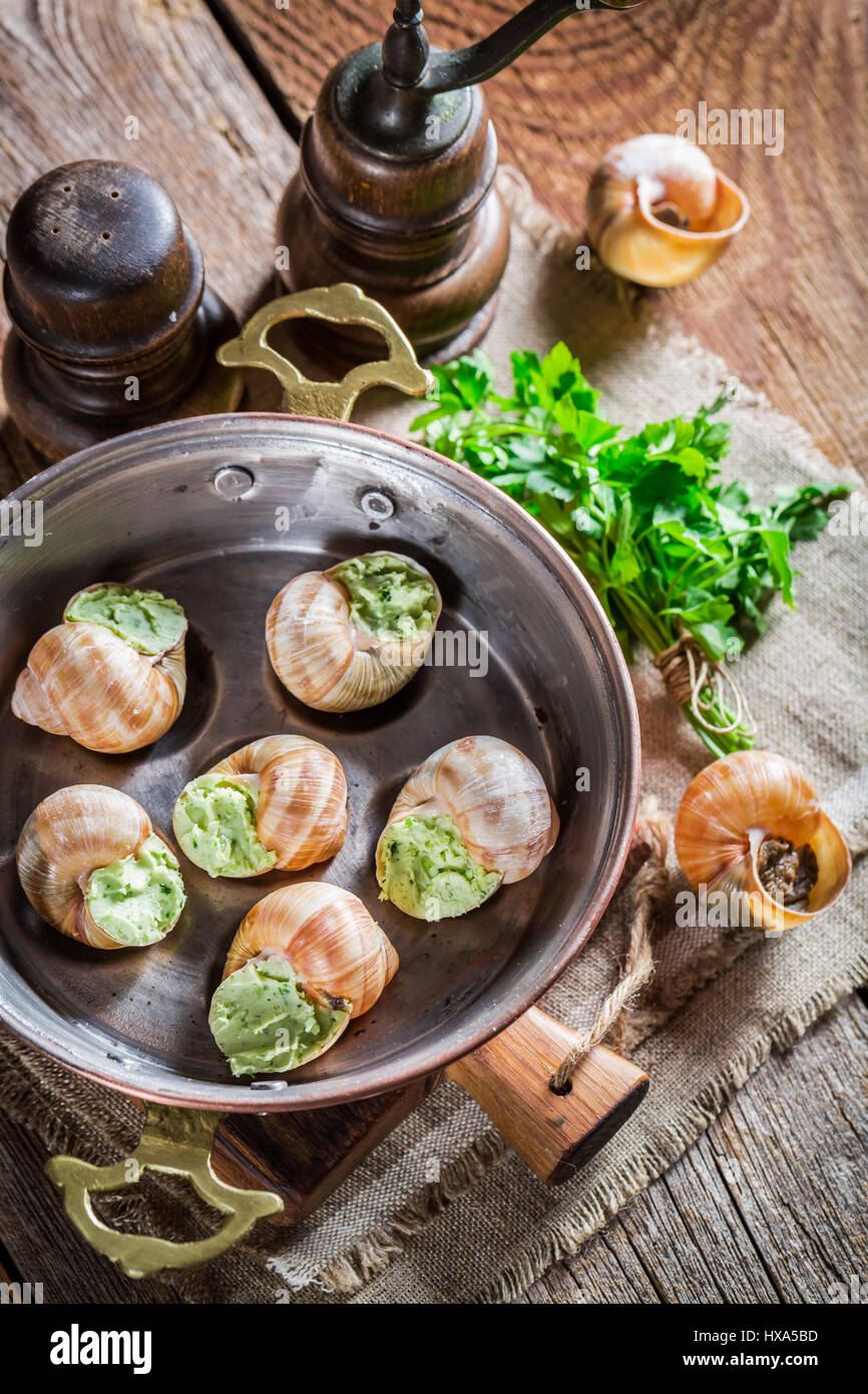 Fresh snails with garlic butter on old wooden table Stock Photo - Alamy