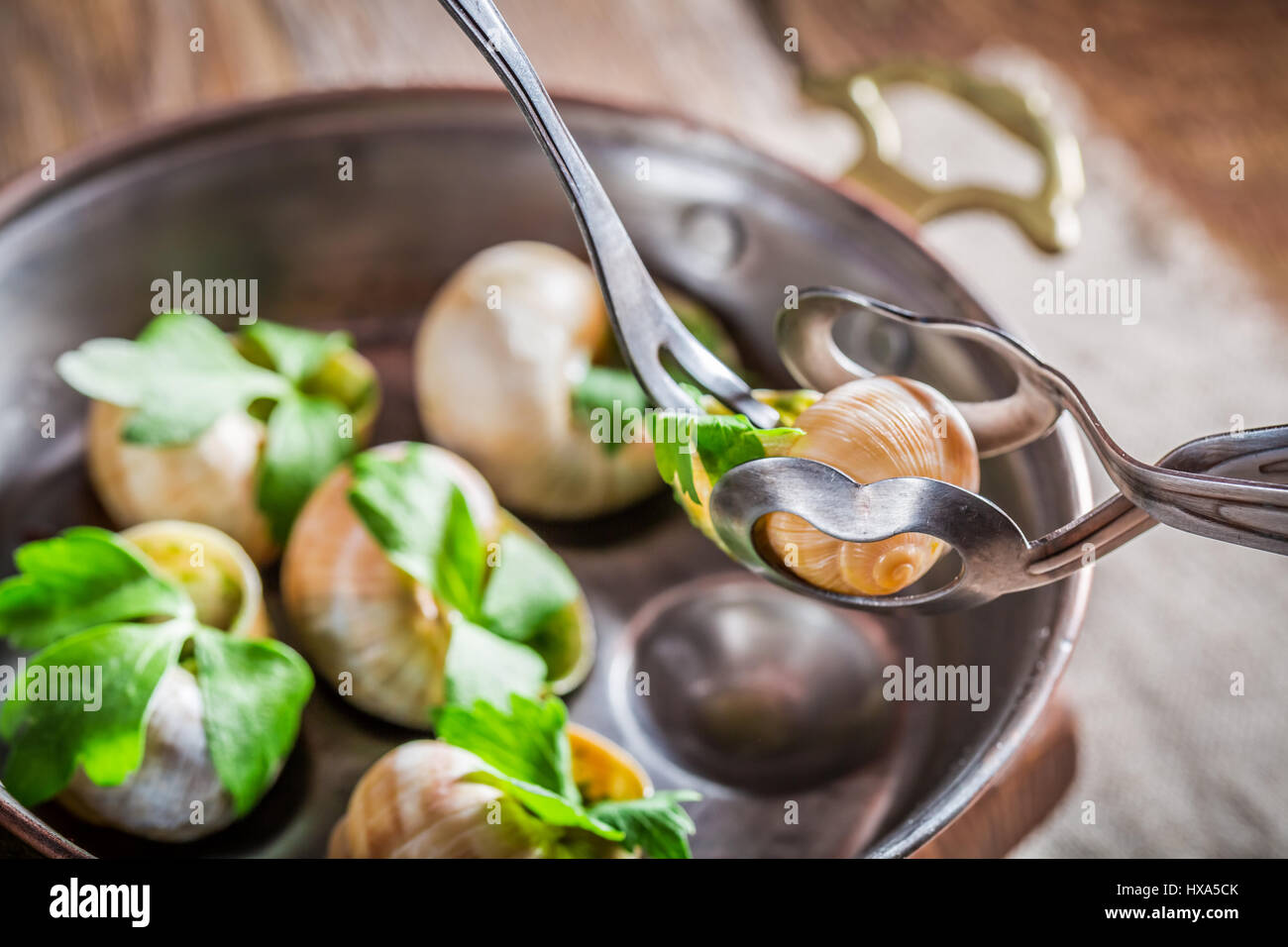 Eating roasted snails on old wooden table Stock Photo - Alamy