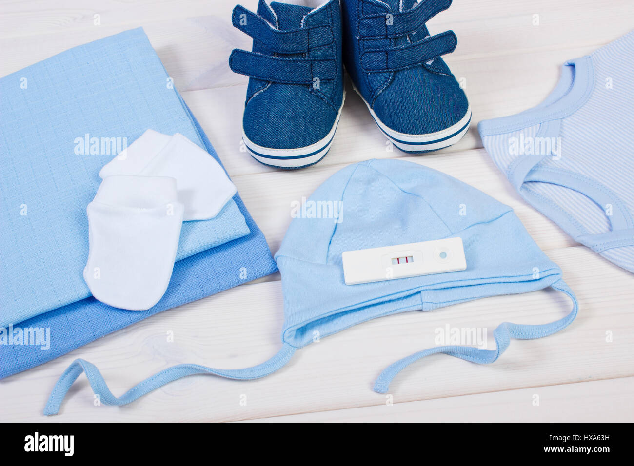 Pregnancy test with positive result and clothing for newborn on boards ...