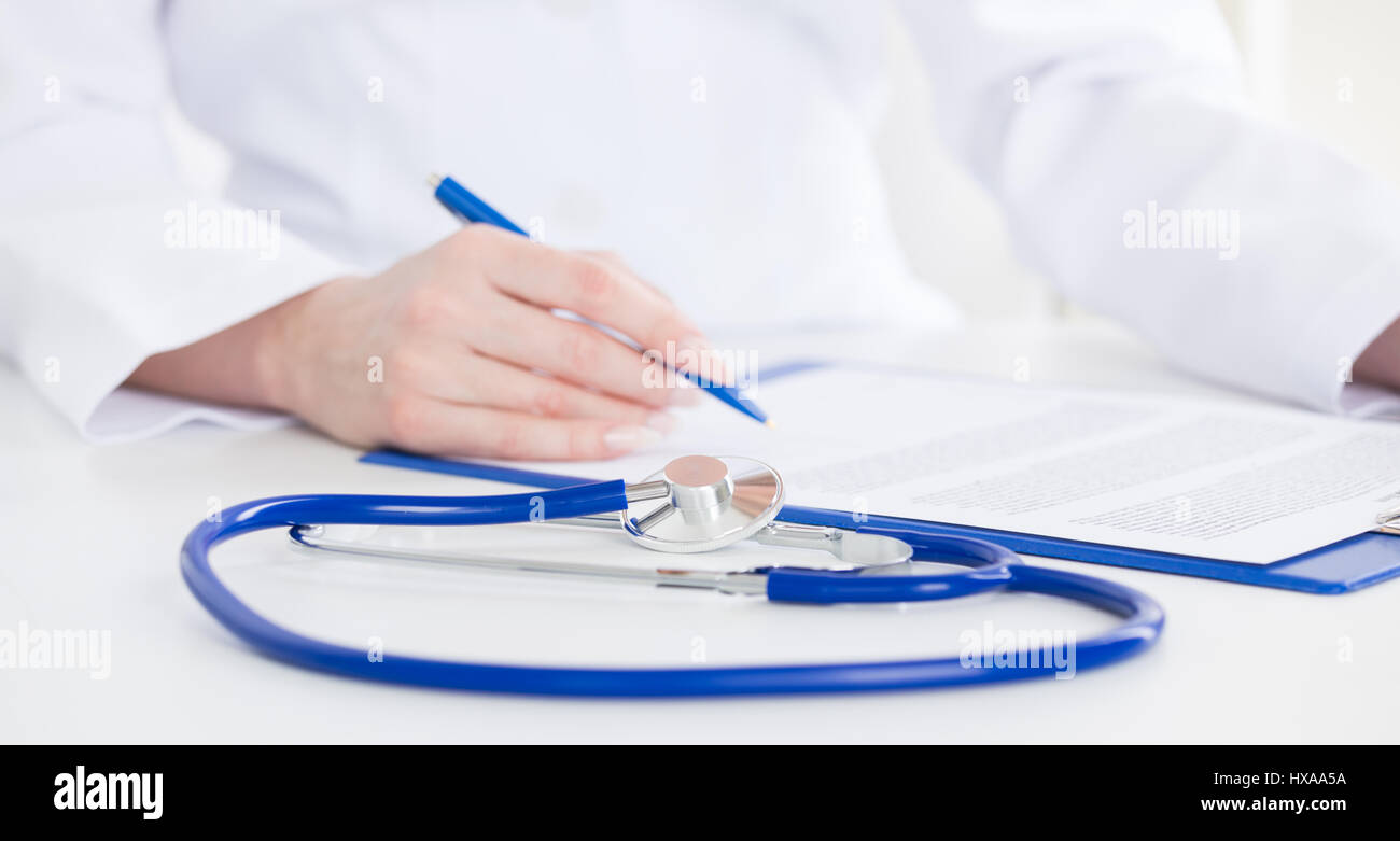 Female doctor with stethoscope writing diagnosis on paper Stock Photo ...
