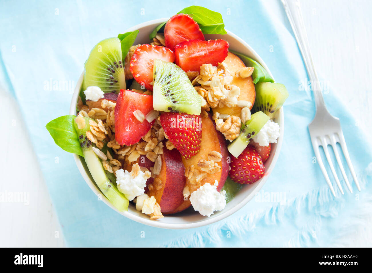 Fresh fruit salad with homemade granola, feta cheese and honey on white ...