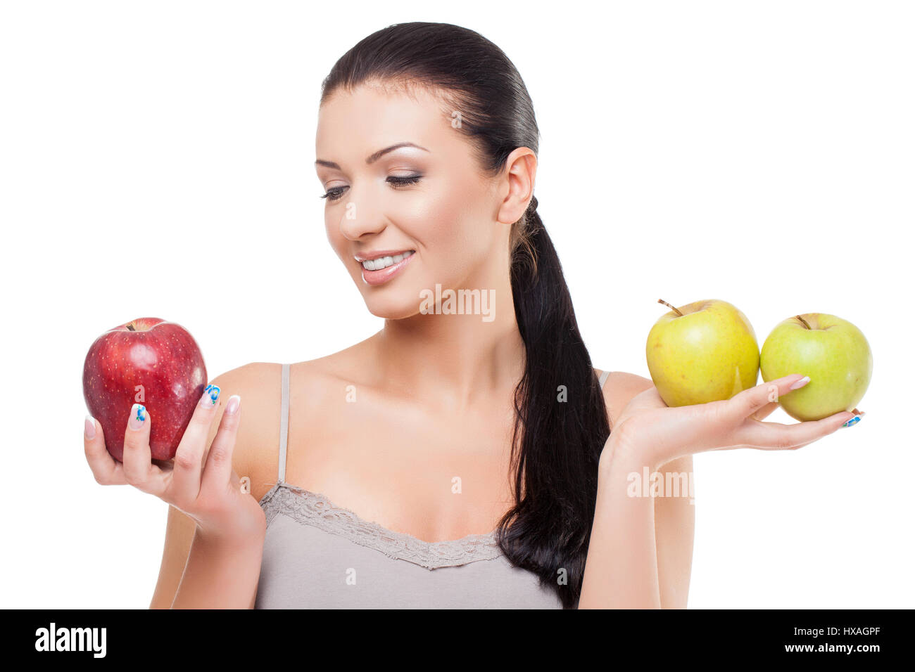 Beautiful happy young woman holding one red and two green apples ...